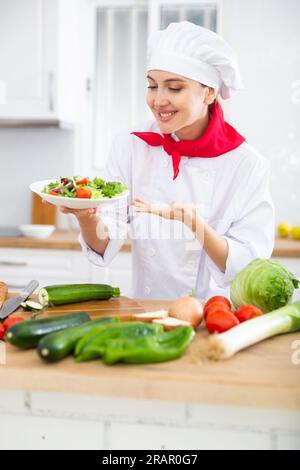 Female chef demonstrating excellent salad in the kitchen Stock Photo ...