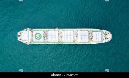 Top-down view of a bulk carrier being loaded with raw materials at an ...