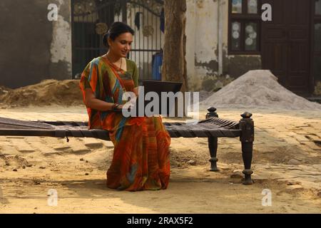 Happy Indian Rural woman sitting on cot outside her home in front yard ...