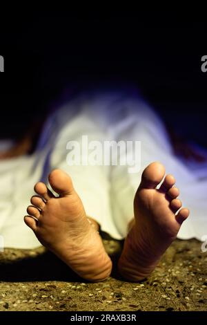 Feet of an Indian or Asian female dead body lying on floor in a dark ...
