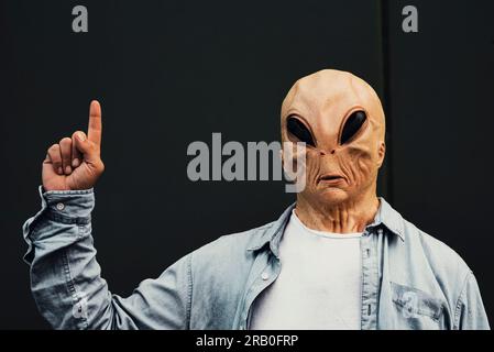Alien mask people against a black background doing hallo gesture Stock ...