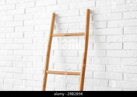 Wooden ladder near white brick wall in room Stock Photo - Alamy