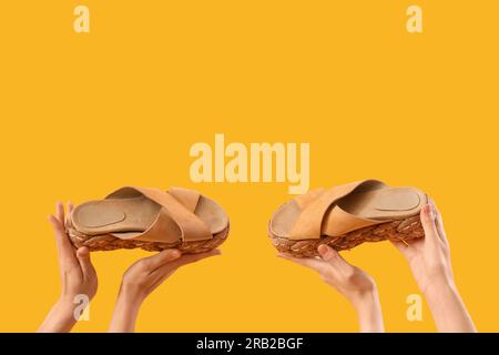 Hands with flip-flops on yellow background Stock Photo - Alamy