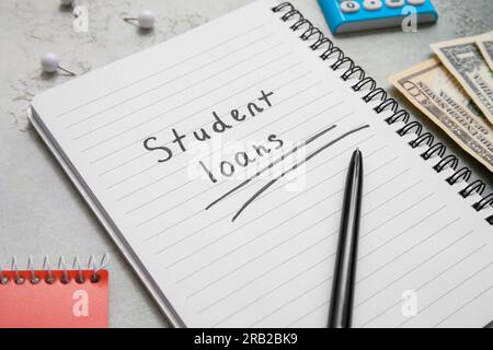 Notebook with text STUDENT LOANS, dollar banknotes, calculator and ...