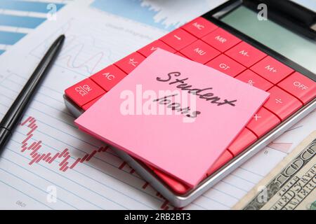 Sticky note with text STUDENT LOANS, calculator, notebooks, charts and ...