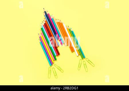 Pencils and paper clips in shape of rocket on yellow background Stock ...