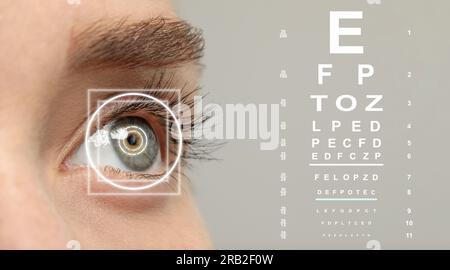Vision test chart and laser reticle focused on man's eye against light ...