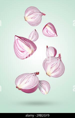 Cut red onions falling on light pink background Stock Photo - Alamy