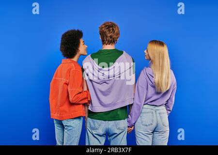 polygamy, back view of polyamory three people, young man and women ...