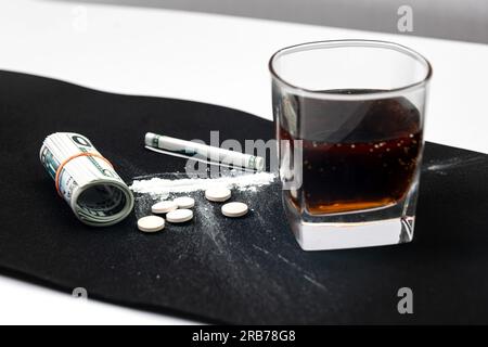 A photo of drugs, tablets, dollar bills, and alcohol in a glass on a ...