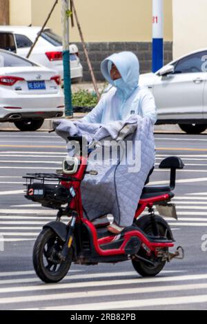 ANYANG, CHINA - JULY 8, 2023 - A pedestrian wearing protective clothing ...