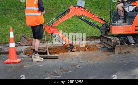 Excavator digging up dirt between cut concrete pavement to repair ...