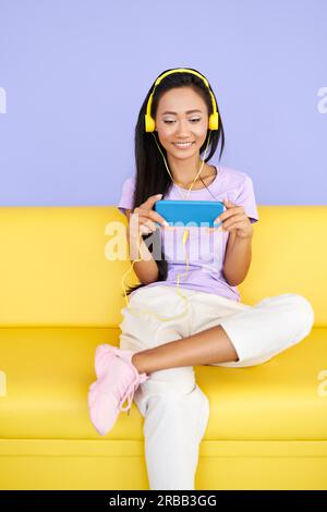 Young Asian woman enjoying video game break while working from home ...