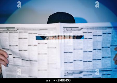 Man hiding watches through the newspaper in the spotlight on studio ...
