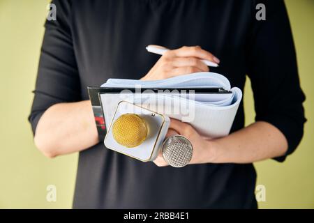 Female journalist at news conference writing notes and holding ...