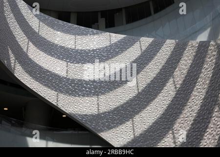 Futuristic atrium with light and shadow, walls clad in white tiles in ...