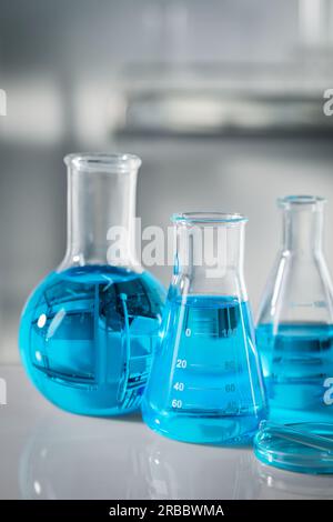 Different laboratory glassware with light blue liquid and microscope on ...