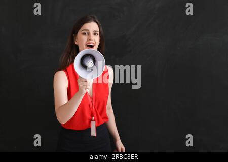 Female teacher shouting into megaphone near blackboard in classroom ...