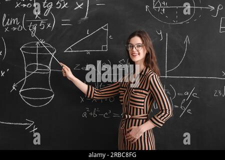 Female Math teacher conducting lesson near blackboard in classroom ...
