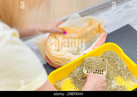 woman pouring used cat litter into trash bag. woman changing cat litter ...