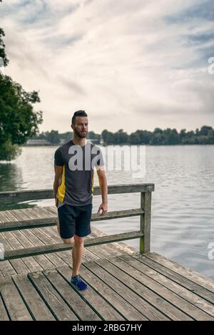 Young man doing stretching exercises on pool deck Stock Photo - Alamy