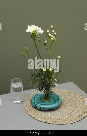 Bowl with beautiful ikebana on table near blue wall Stock Photo - Alamy