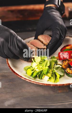 Professional chef arranging food plate with meat and vegetables Stock ...