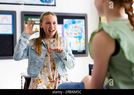 Happy diverse schoolchildren using sign language in school classroom ...