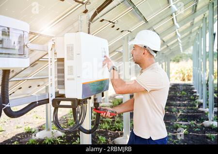 Male worker checking if solar inverter working right. Young man ...