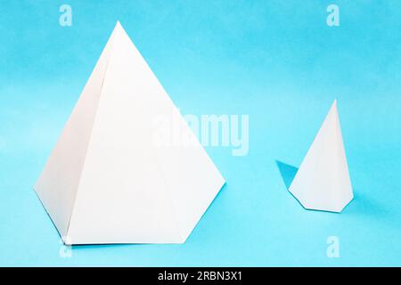 pair of different hand-crafted paper pyramids on turquoise blue ...