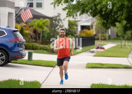 energetic running man races down neighbourhood. running man enjoys the ...