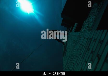 Silhouette of police officer in tactical gear descending from a height ...