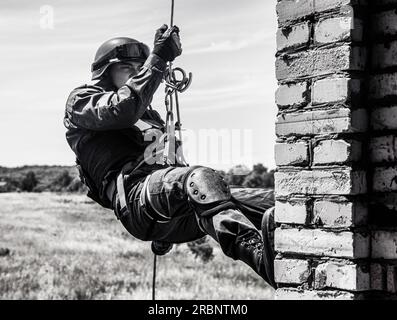Silhouette of police officer in tactical gear descending from a height ...