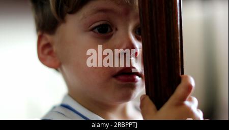 Fearful child hiding behind furniture feeling scared kid being afraid ...