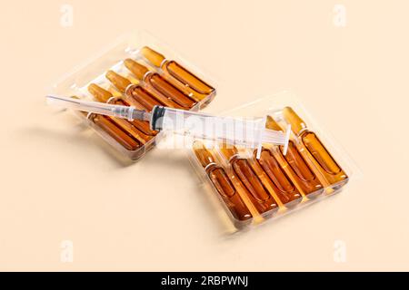 Many ampules in packing with syringe on beige background Stock Photo ...