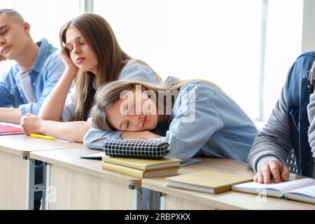 Tired sleepy classmates sitting at desks in classroom Stock Photo - Alamy