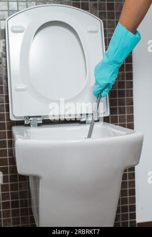 Person wearing a turquoise rubber glove cleaning under the rim of a ...