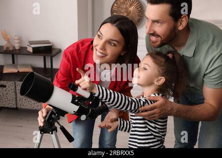 Happy family using telescope to look at stars in room Stock Photo - Alamy