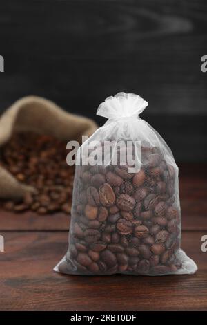 Scented sachet and coffee beans on grey table against black background ...