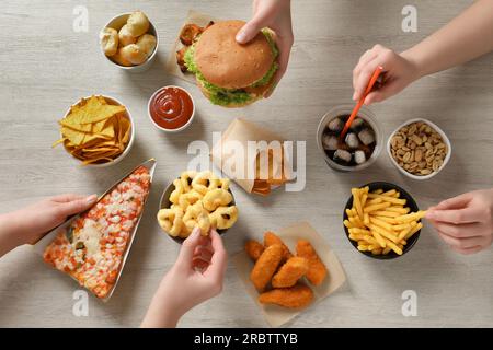 Friends eating french fries, burger and other fast food at white wooden ...