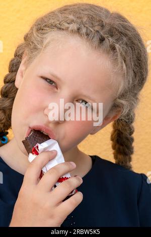 Schoolgirl eating a chocolate bar Stock Photo - Alamy