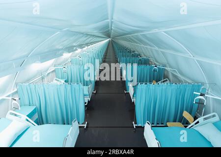 Rows of hospital beds separated by curtains in a field hospital. Empty ...