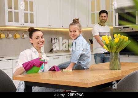 Spring cleaning. Parents with their daughter tidying up living room ...