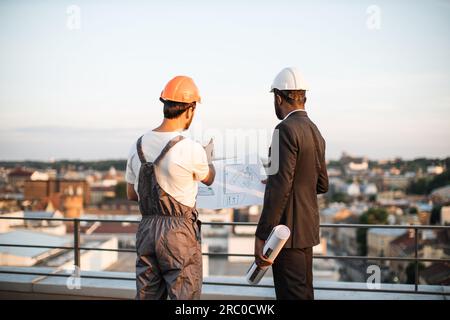 African AMerican engineer examining fresh beer in glass and discussing ...