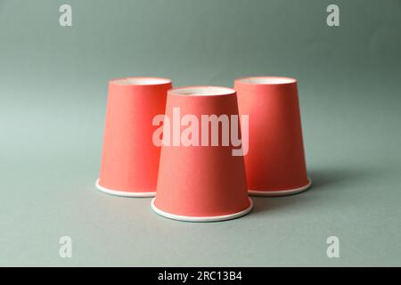 Three red cups on pale olive background. Thimblerig game Stock Photo ...