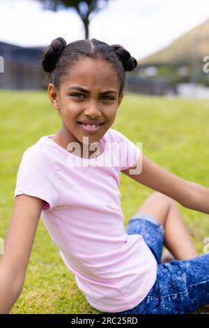 Portrait of African American schoolgirl looking at camera while sitting ...