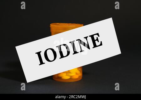 Paper note with word Iodine, bottle and pills on light blue background ...