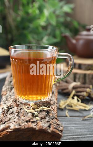 Aromatic licorice tea in cup, dried sticks of licorice root and powder ...