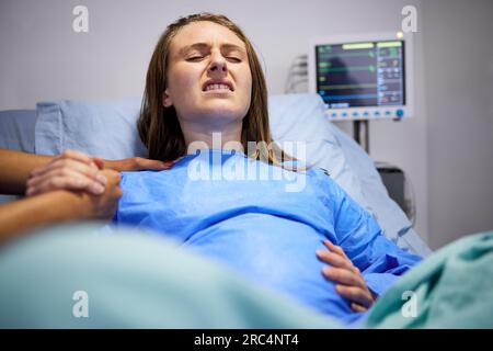 Pregnant woman, clinic and labor with push, holding hands or support in ...