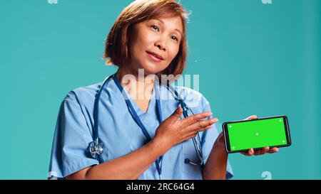 BIPOC woman holding chroma key green screen phone, showing thumbs up ...